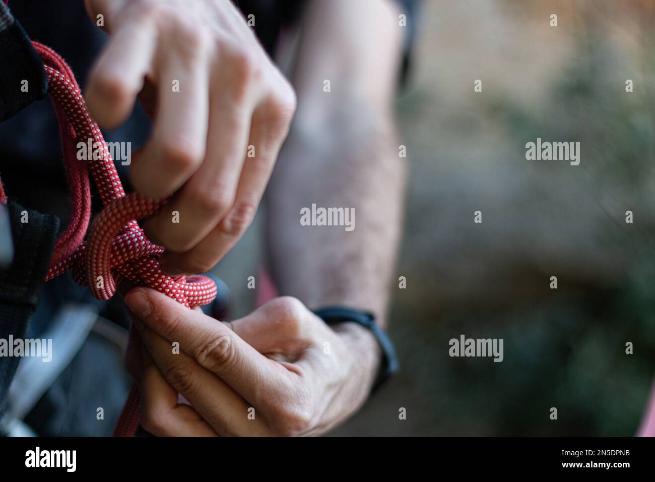 An alpinist tying a rope on his climbing equipment Stock Photo - Alamy