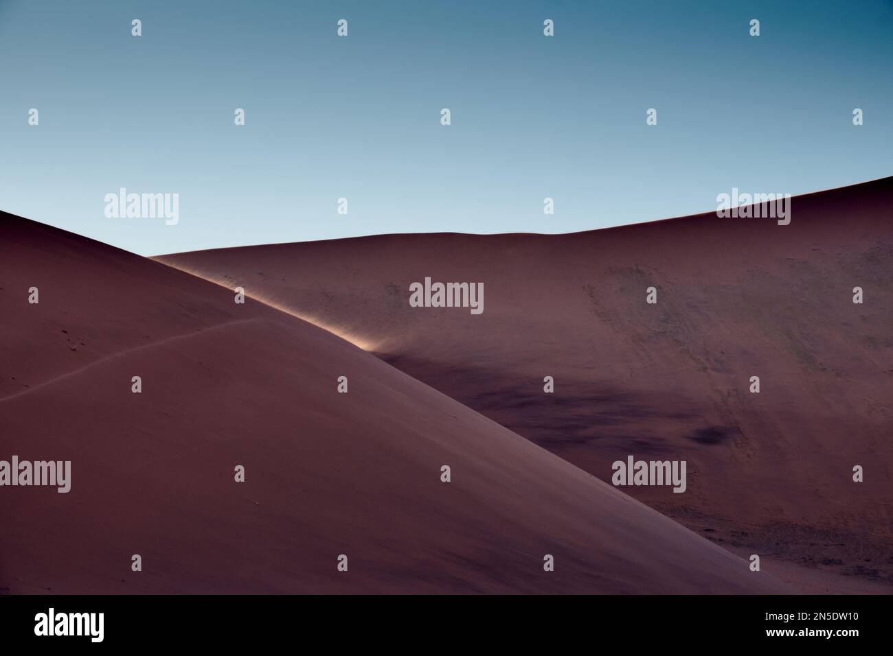 The rising sun backlights the red dunes at Sossusvlei with highlighted ...