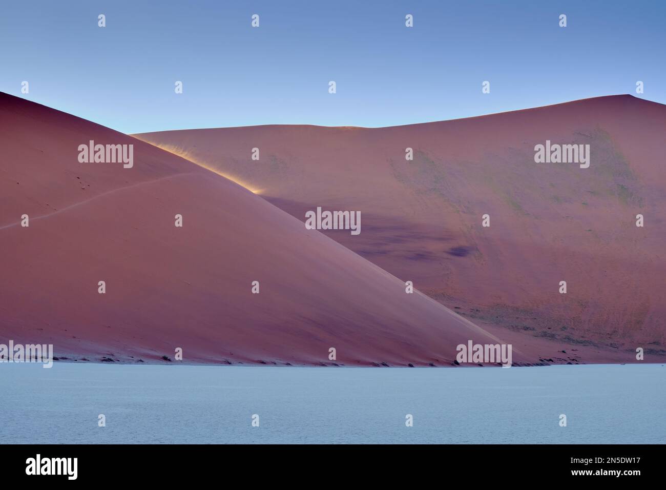 The rising sun backlights the red dunes at Sossusvlei with highlighted ...