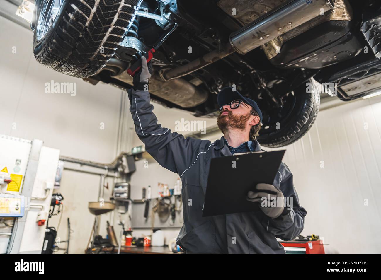 mechanic while chassis inspection checking a car and writing details ...