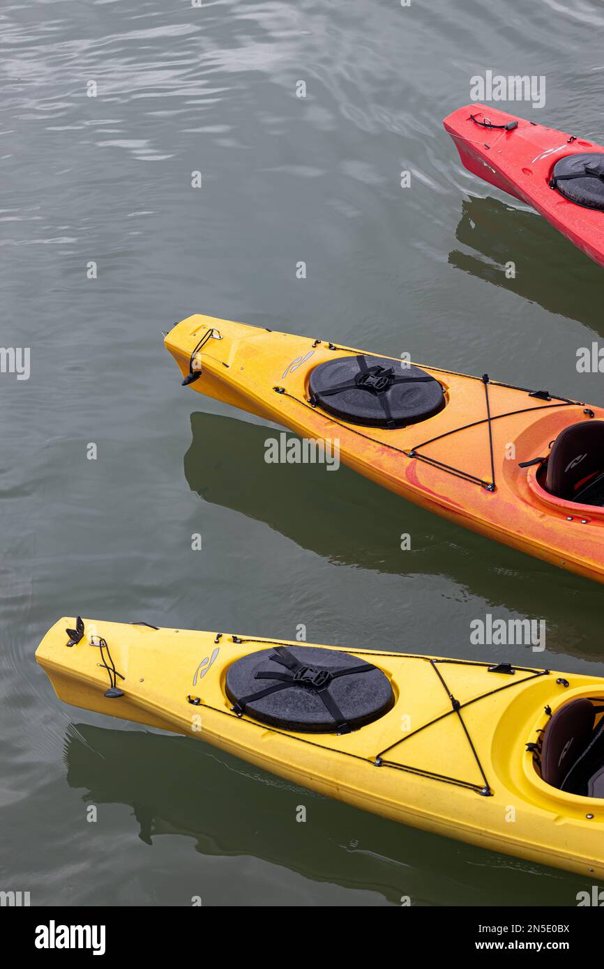 A vertical closeup of colorful kayaks on the water surface Stock Photo ...