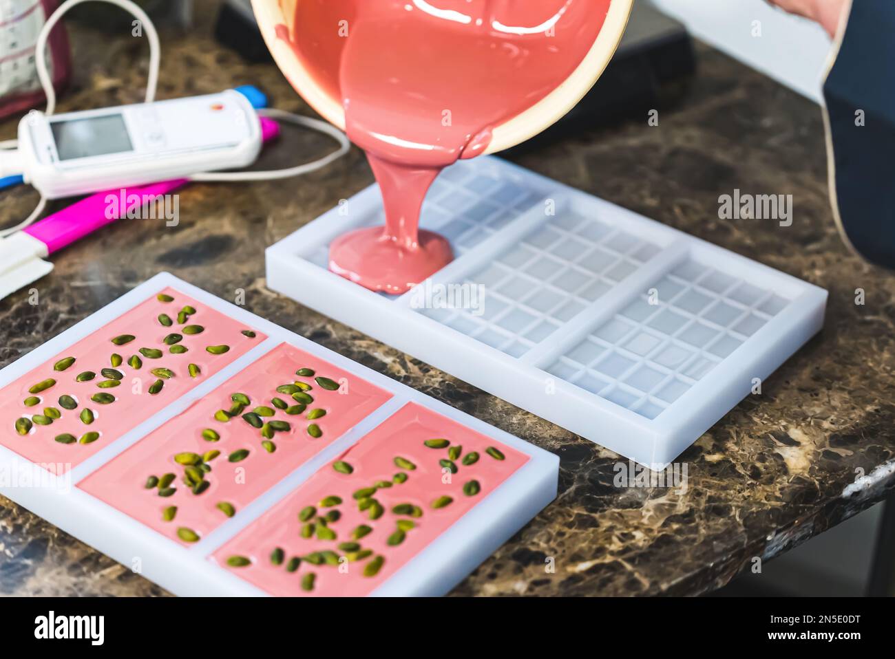Craft pink chocolate being poured into a bar form, molding process ...