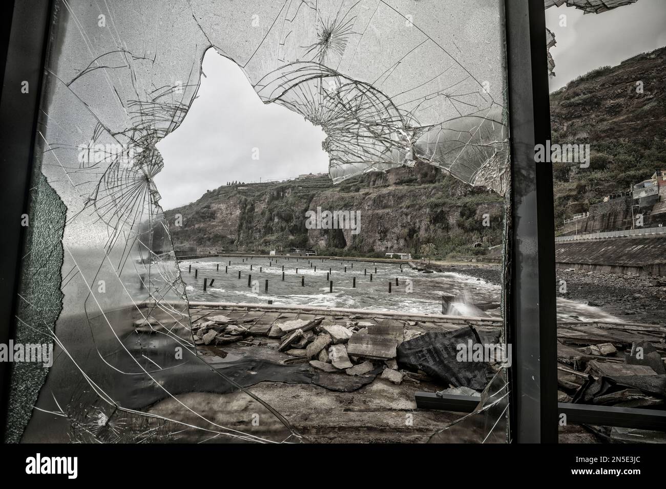 A closeup of a window with broken glass overlooking a rocky beach Stock ...