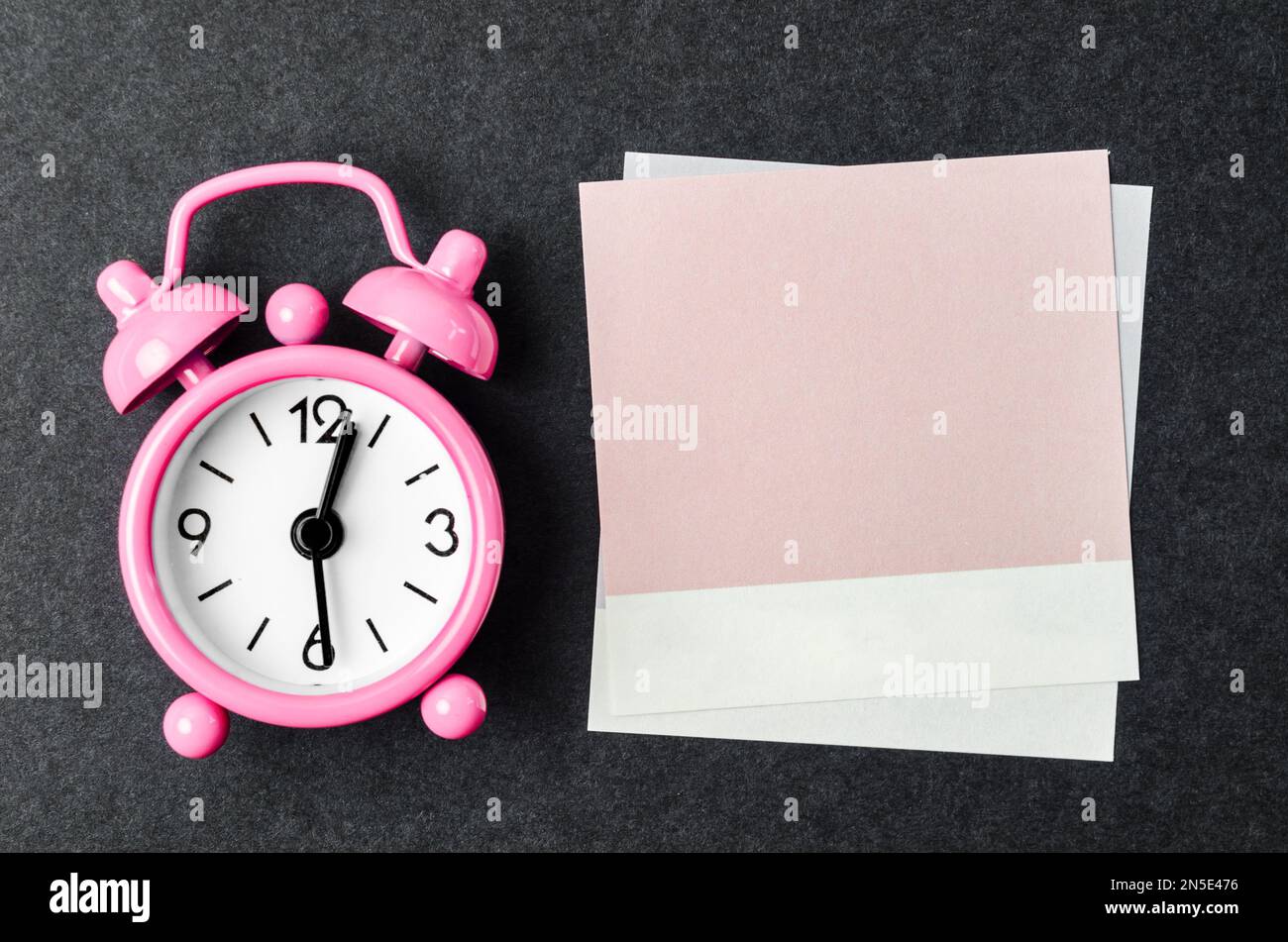 Blank reminder note and alarm clock on black background, space for text ...