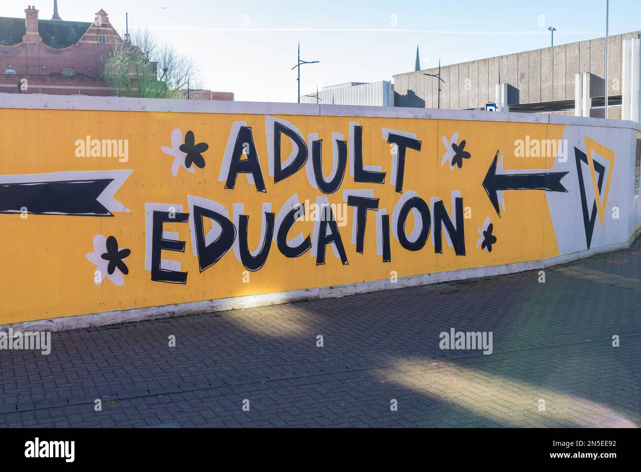 Black and gold sign painted on wooden fence with arrows point to Adult ...
