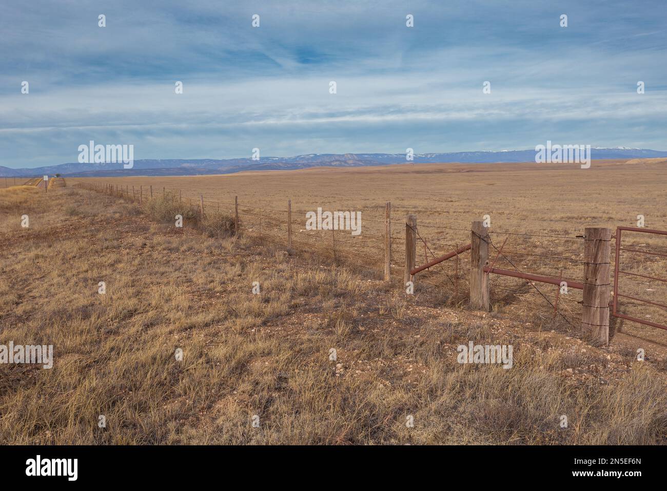 Vintage cattle fence cutting through open pasture with clear sky in ...