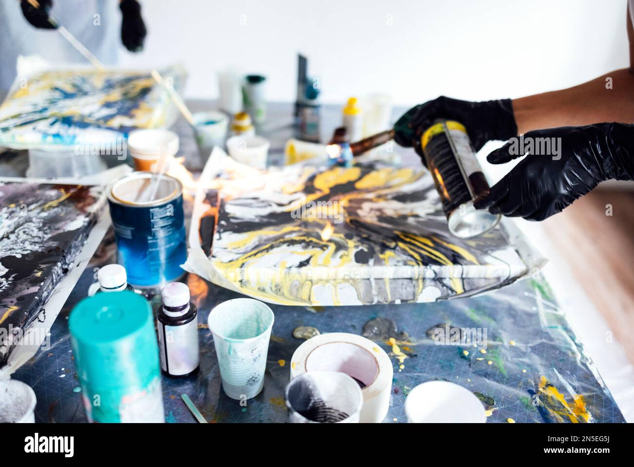 A woman uses a gas burner to draw in Fluid Art. Process of creating a ...