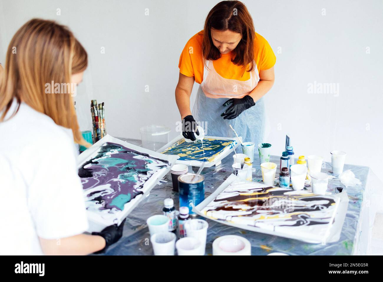Master class on an Acrylic Fluid Pouring. Young women paint with liquid ...