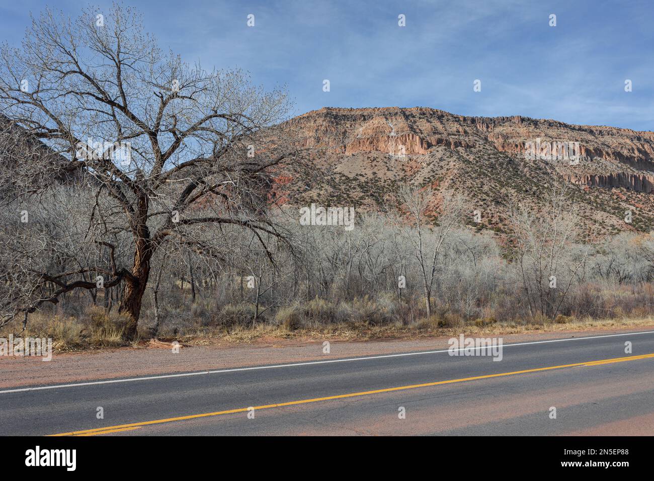 Highway crossing in front of flat-topped mountain range with clear blue ...