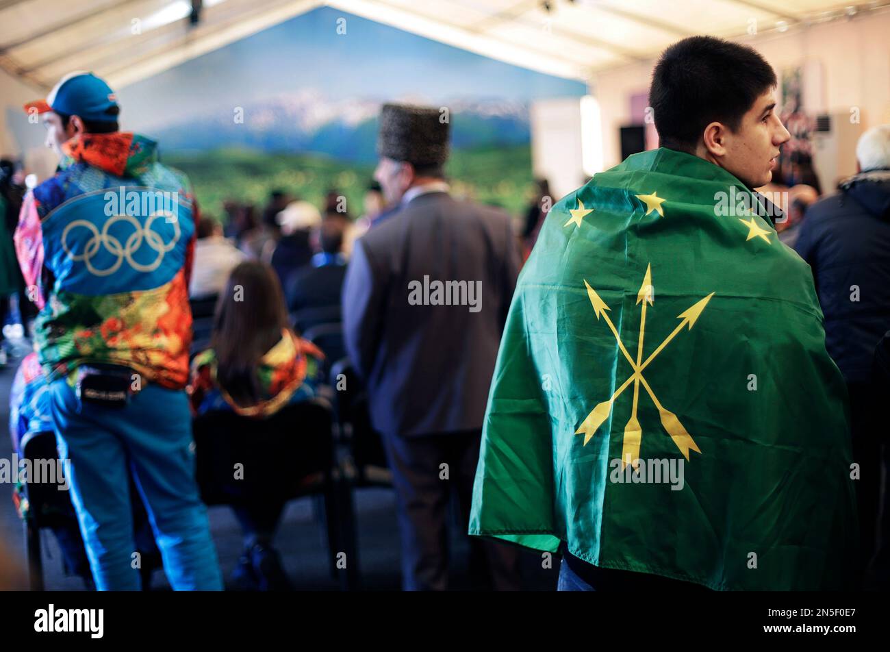 Timur Achmizov, right, wears the Circassian flag draped over his ...