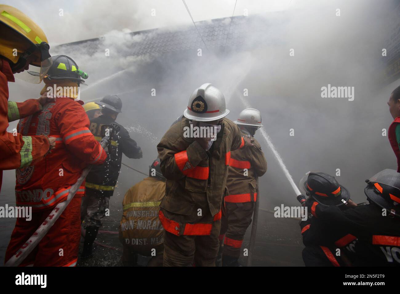 A Filipino fireman covers his nose to avoid inhaling the thick smoke as ...