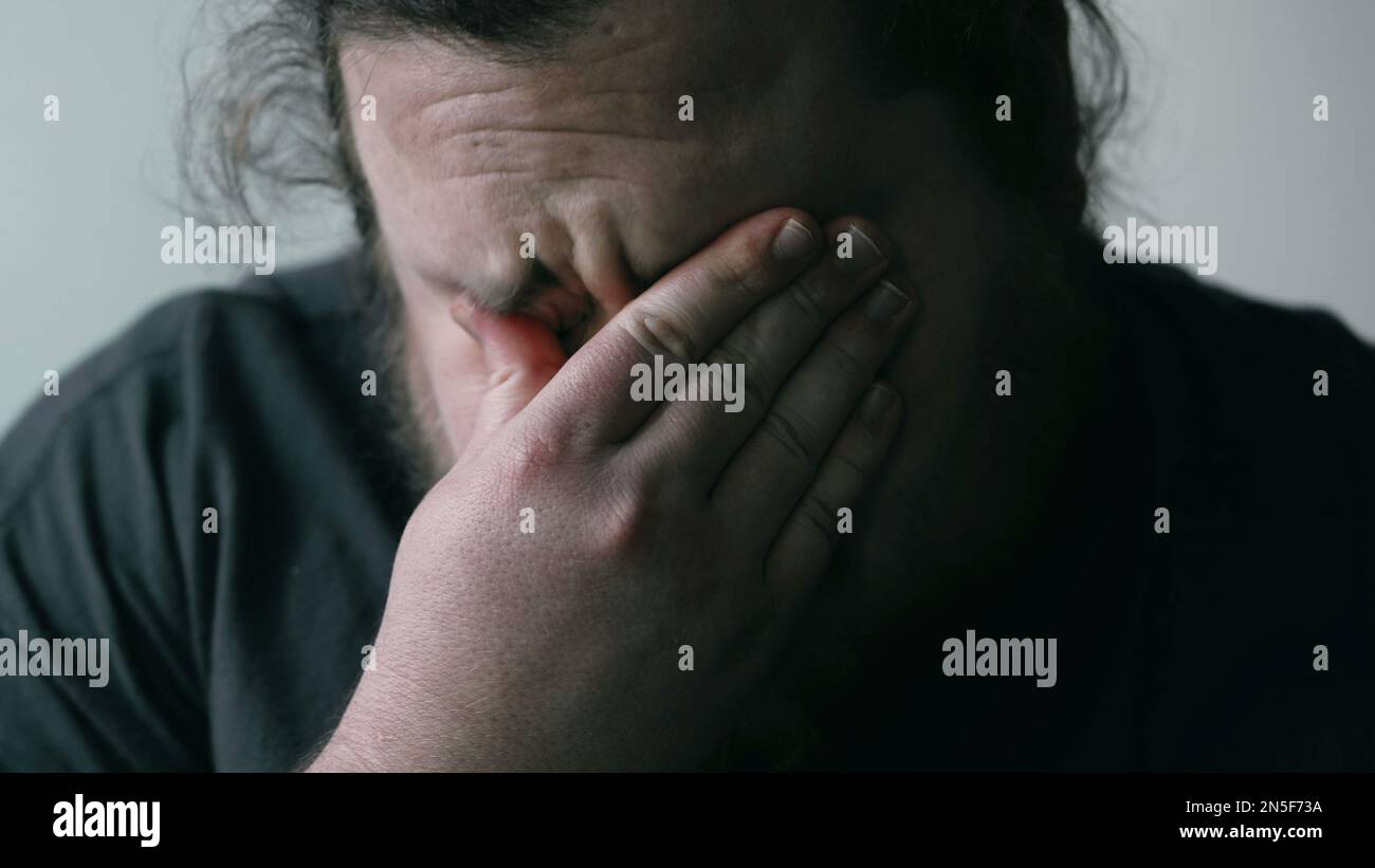 Preoccupied man suffering from mental pain. Close up face of a worried ...