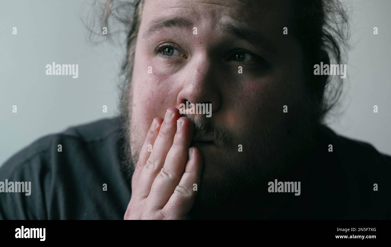 Preoccupied man suffering from mental pain. Close up face of a worried ...