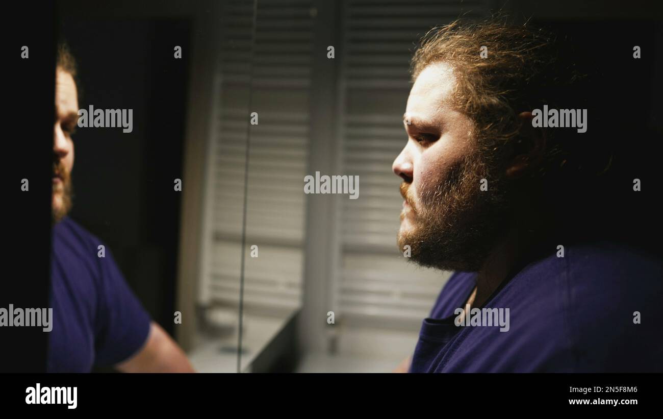 One desperate young man suffering from stress in front of mirror ...