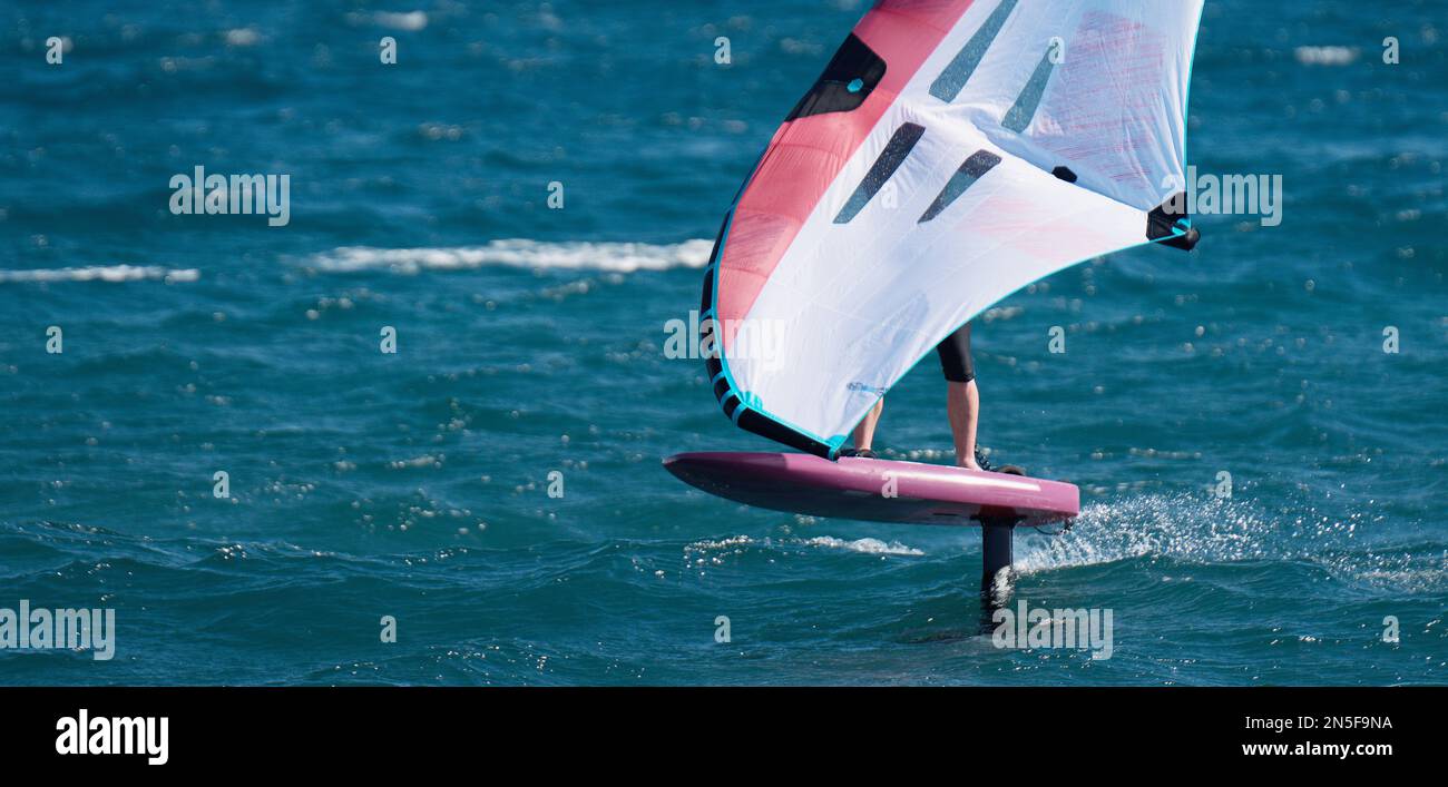 A man is wing foiling using handheld inflatable wings and hydrofoil ...