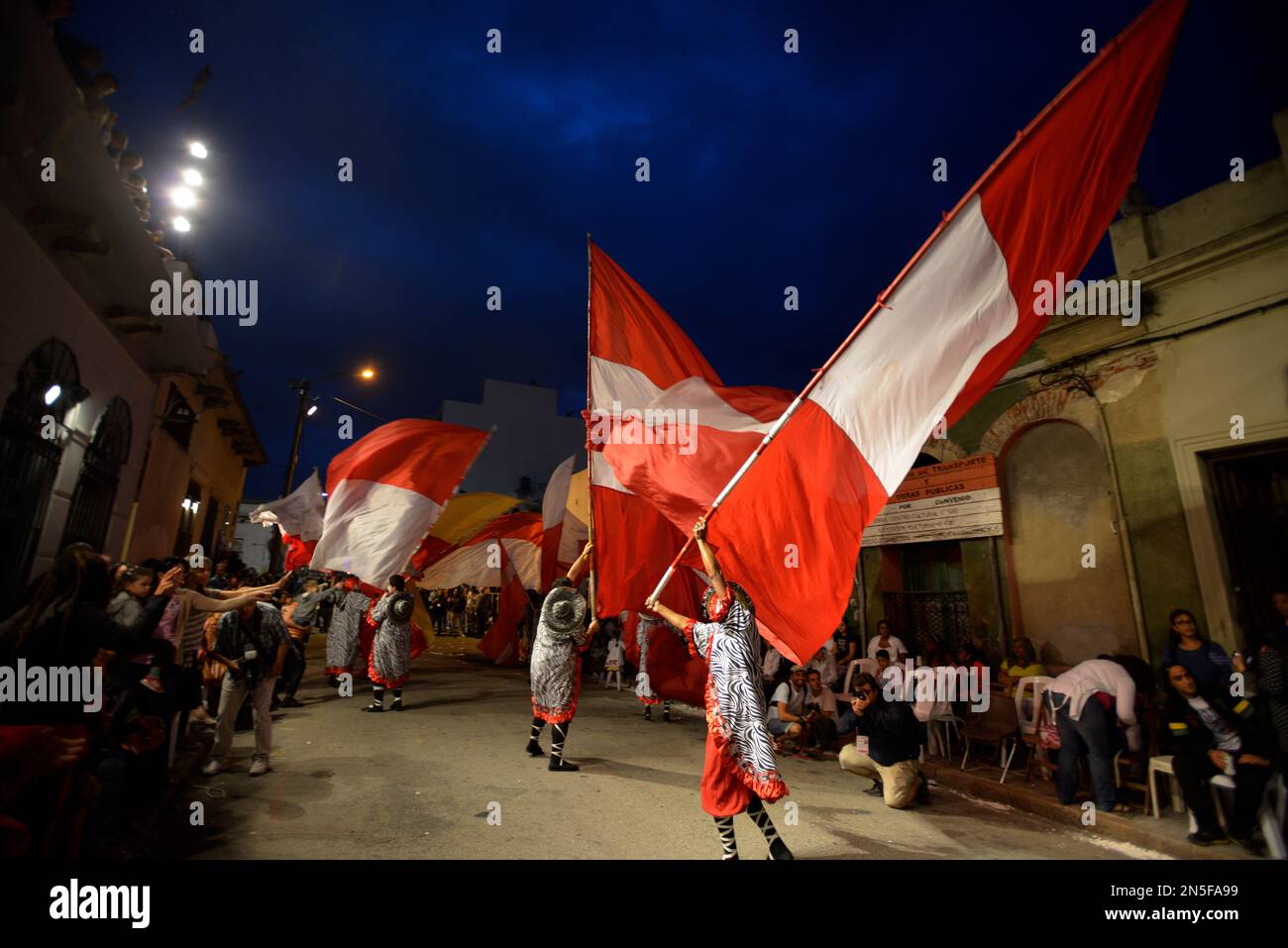 Performers wave red and white banners in Las Llamadas or Calls parade ...
