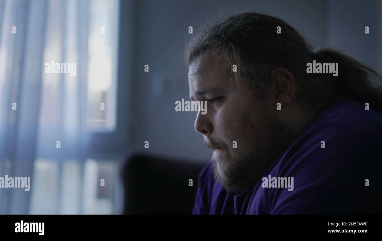 One worried overweight man at home with preoccupied expression. Profile ...