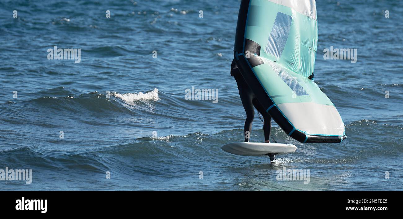 A man is wing foiling using handheld inflatable wings and hydrofoil ...