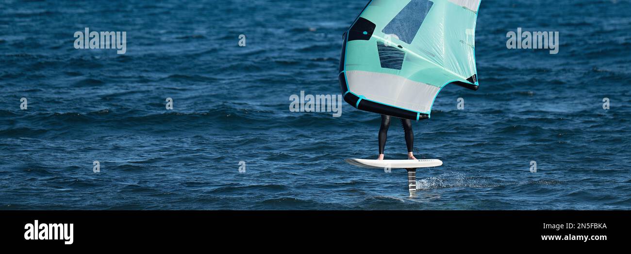 A man is wing foiling using handheld inflatable wings and hydrofoil ...