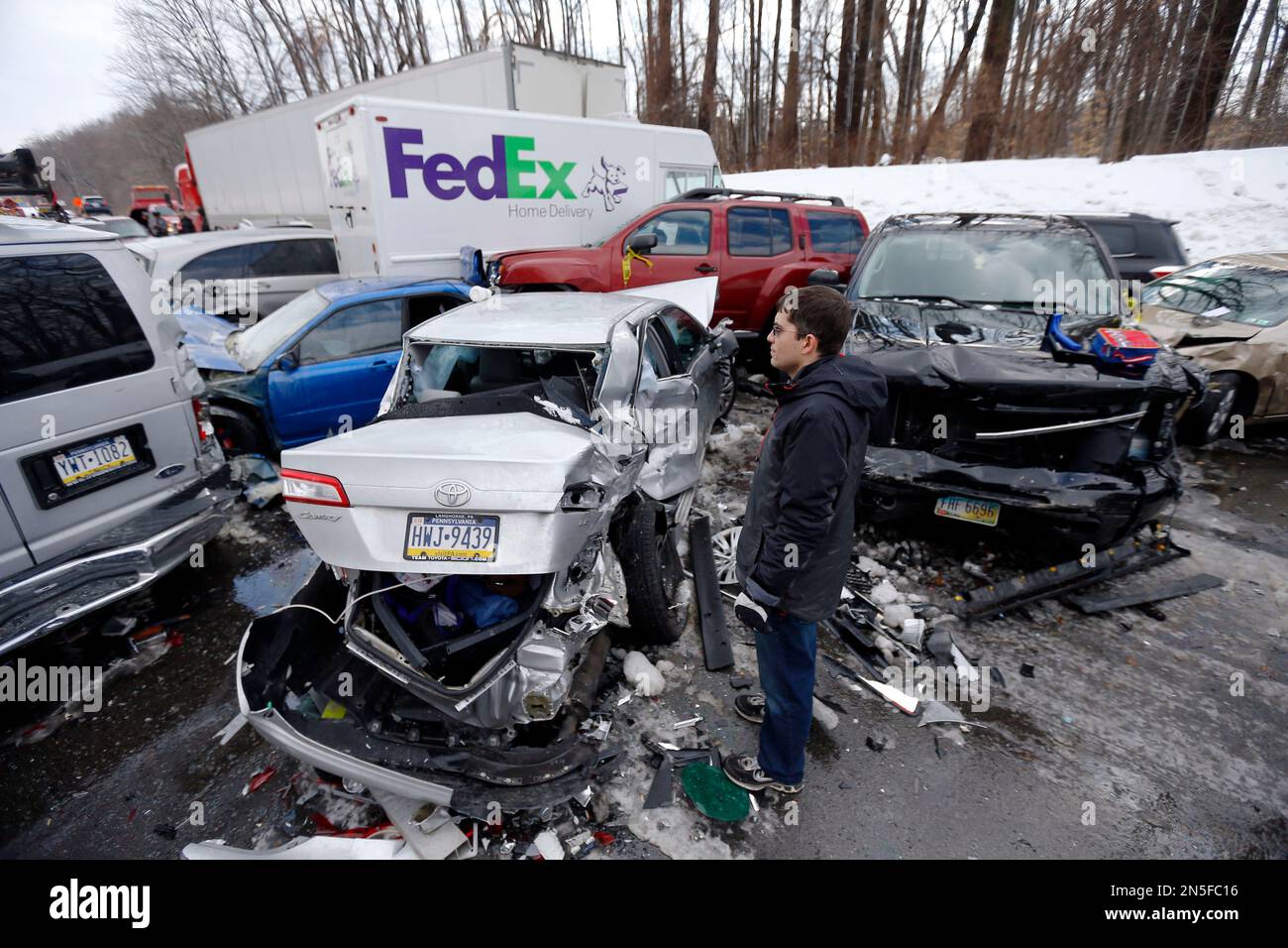 A man inspects vehicles piled up in an accident, Friday, Feb. 14, 2014, in Bensalem, Pa. Traffic ...