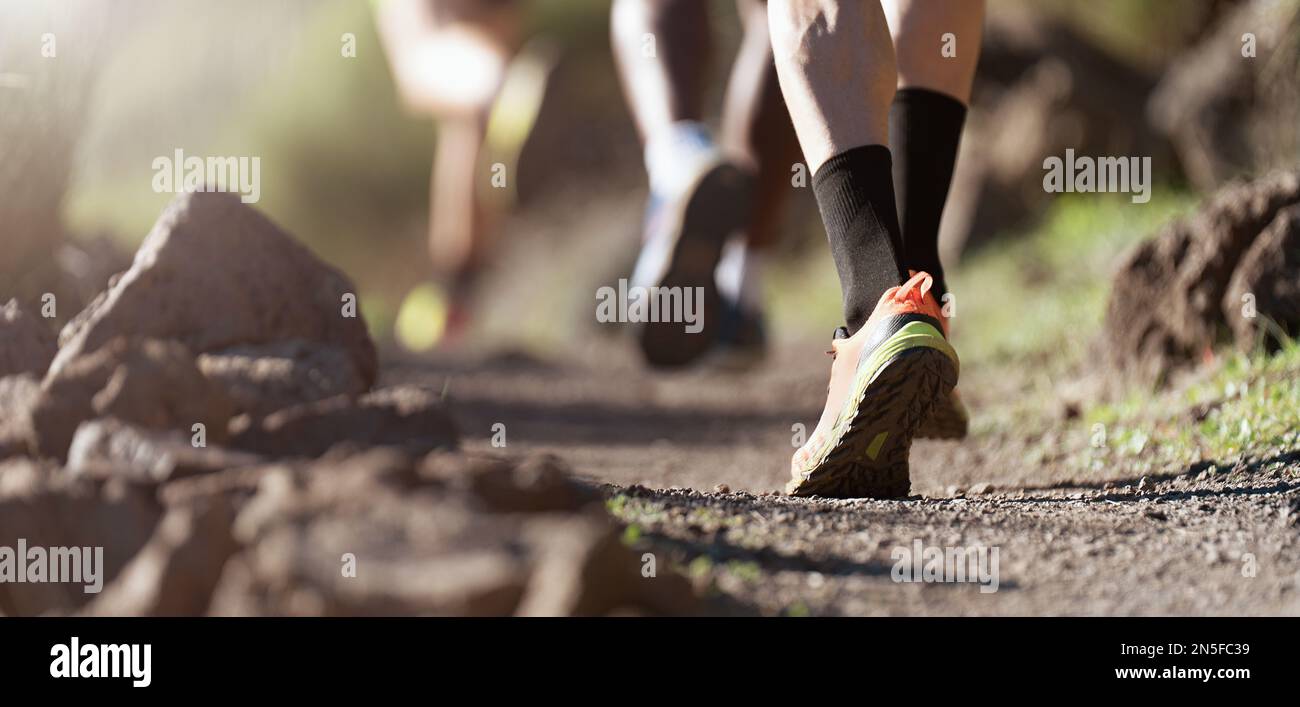 Group of young adults competition and running together through trails ...