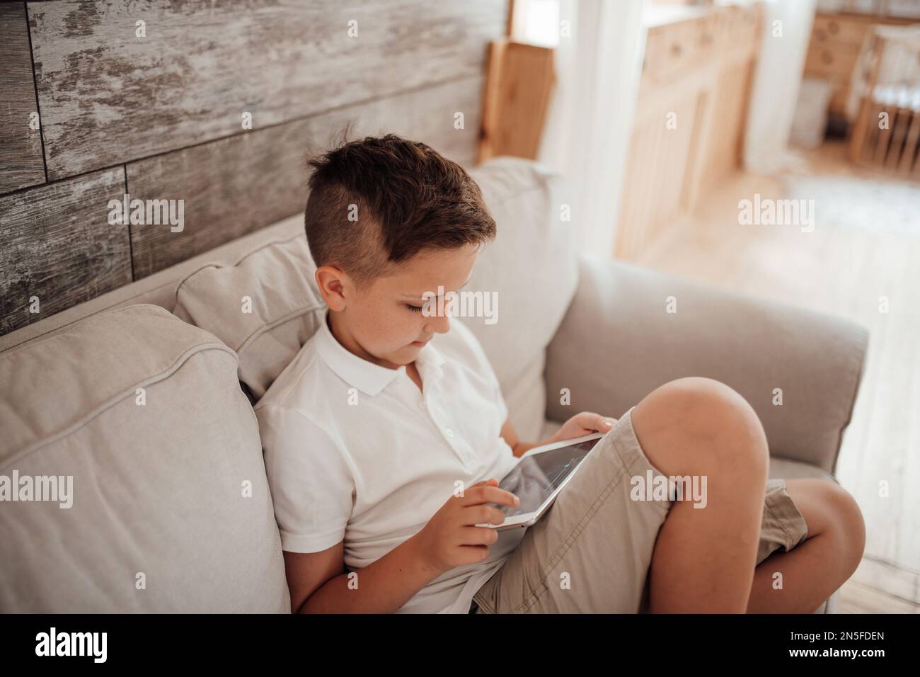 Gen Z boy using wireless technology at apartment in neutrals tones ...