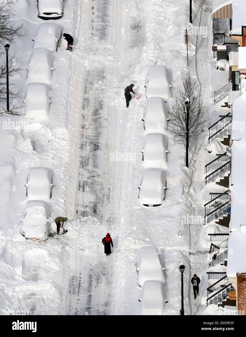 People dig out vehicles buried in snow in downtown Albany, N.Y., on ...