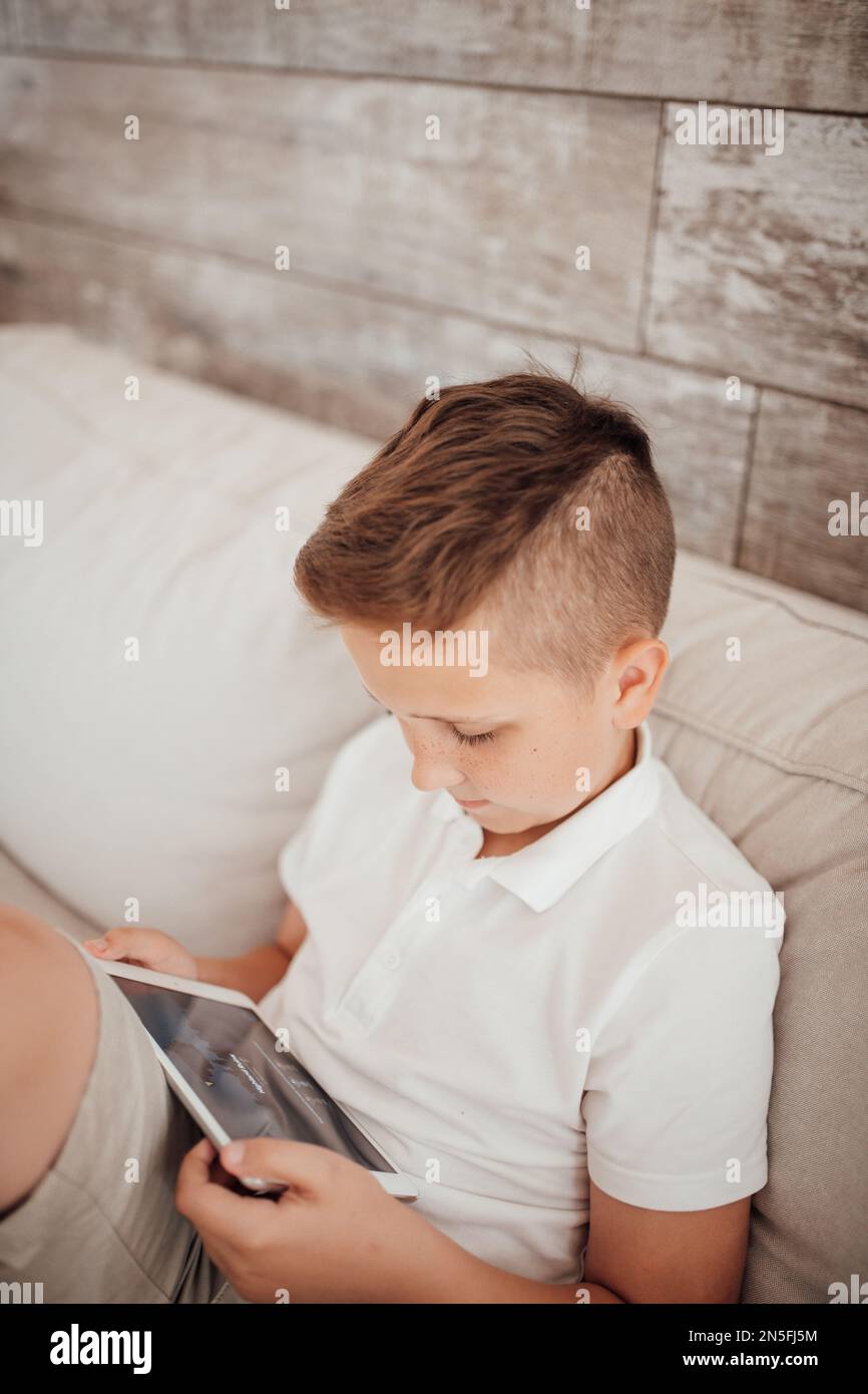 Gen Z boy using wireless technology at apartment in neutrals tones ...