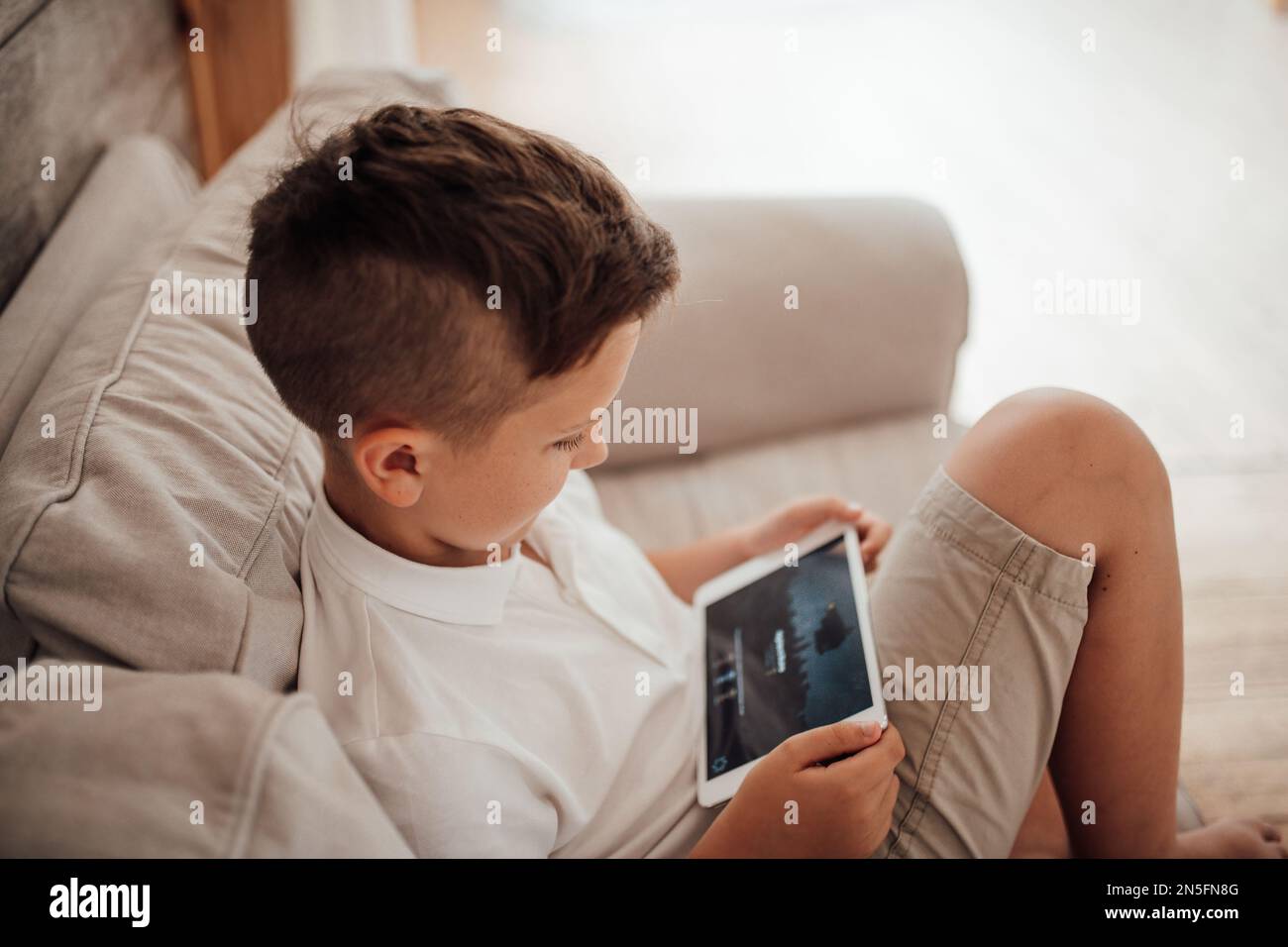 Gen Z boy using wireless technology at apartment in neutrals tones ...