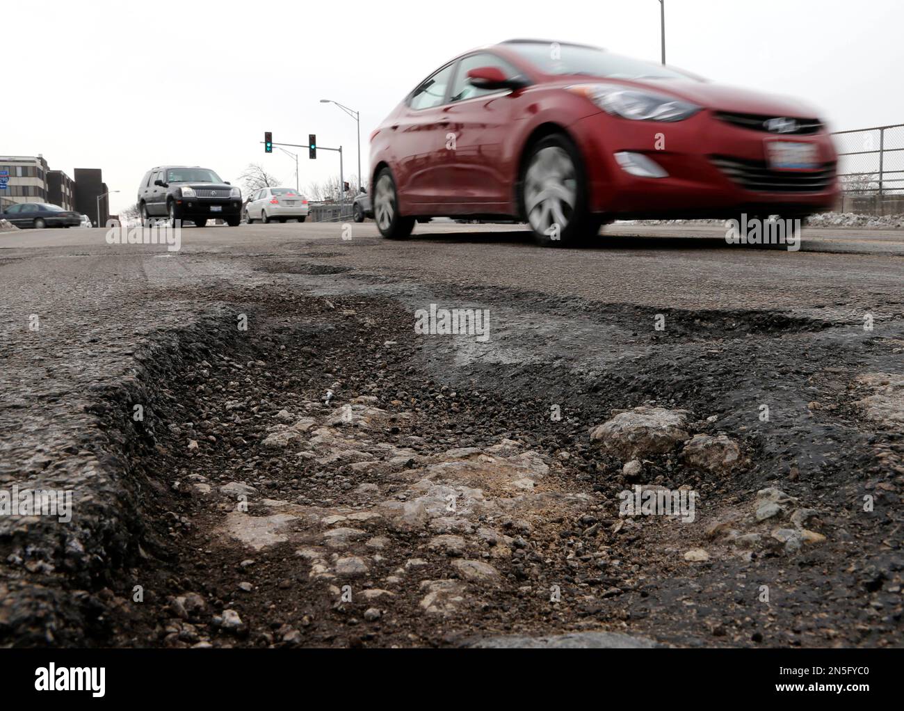 Motorists traveling on Chicago's Austin Ave. dodge potholes as the ...