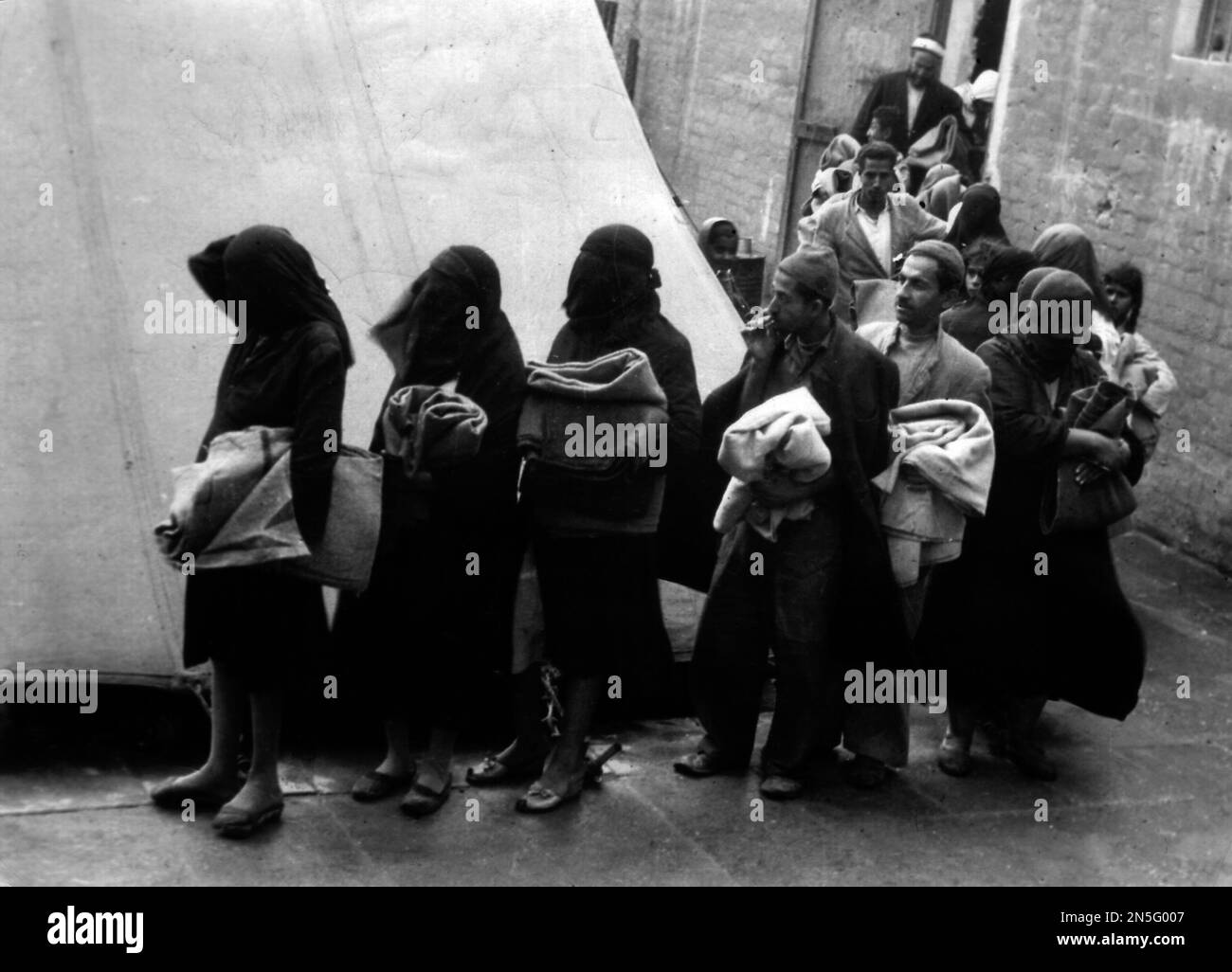 Veiled Arab women and men receive their first allotment of blankets ...