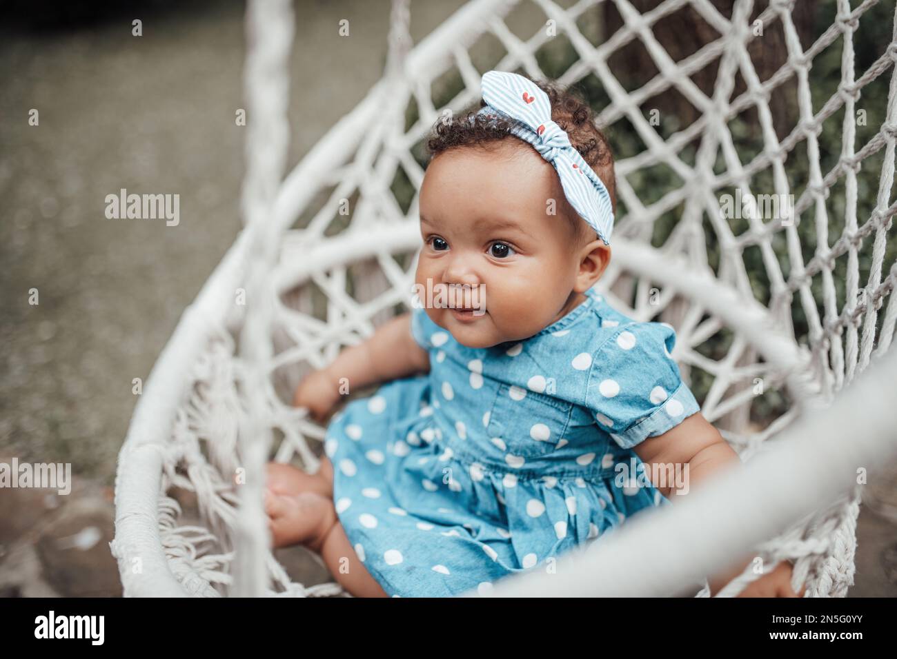 Swarthy little girl in blue polka dot dress has positive emotion ...