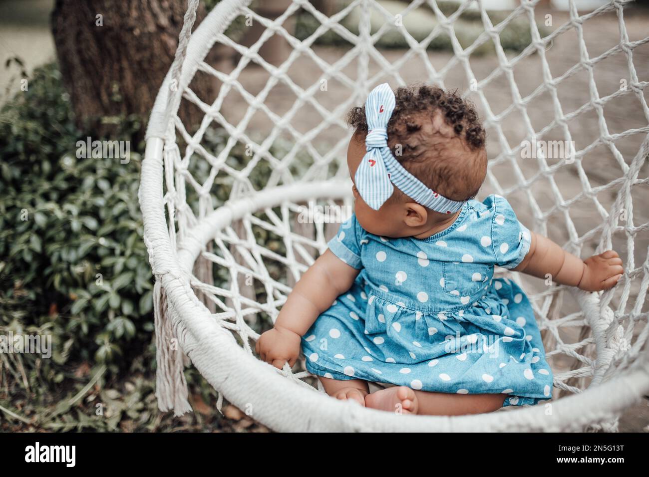 Swarthy little girl in blue polka dot dress has positive emotion ...