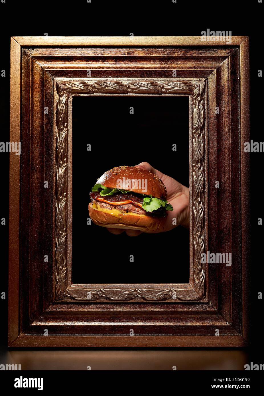 A vertical shot of a person holding a burger through a vintage wooden ...