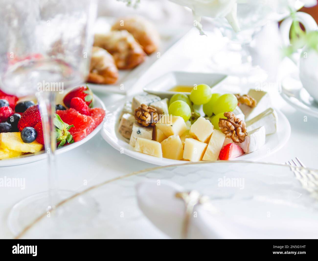 Table served for banquet. Plates with fruits and appetizers, transparent modern stylish wine ...