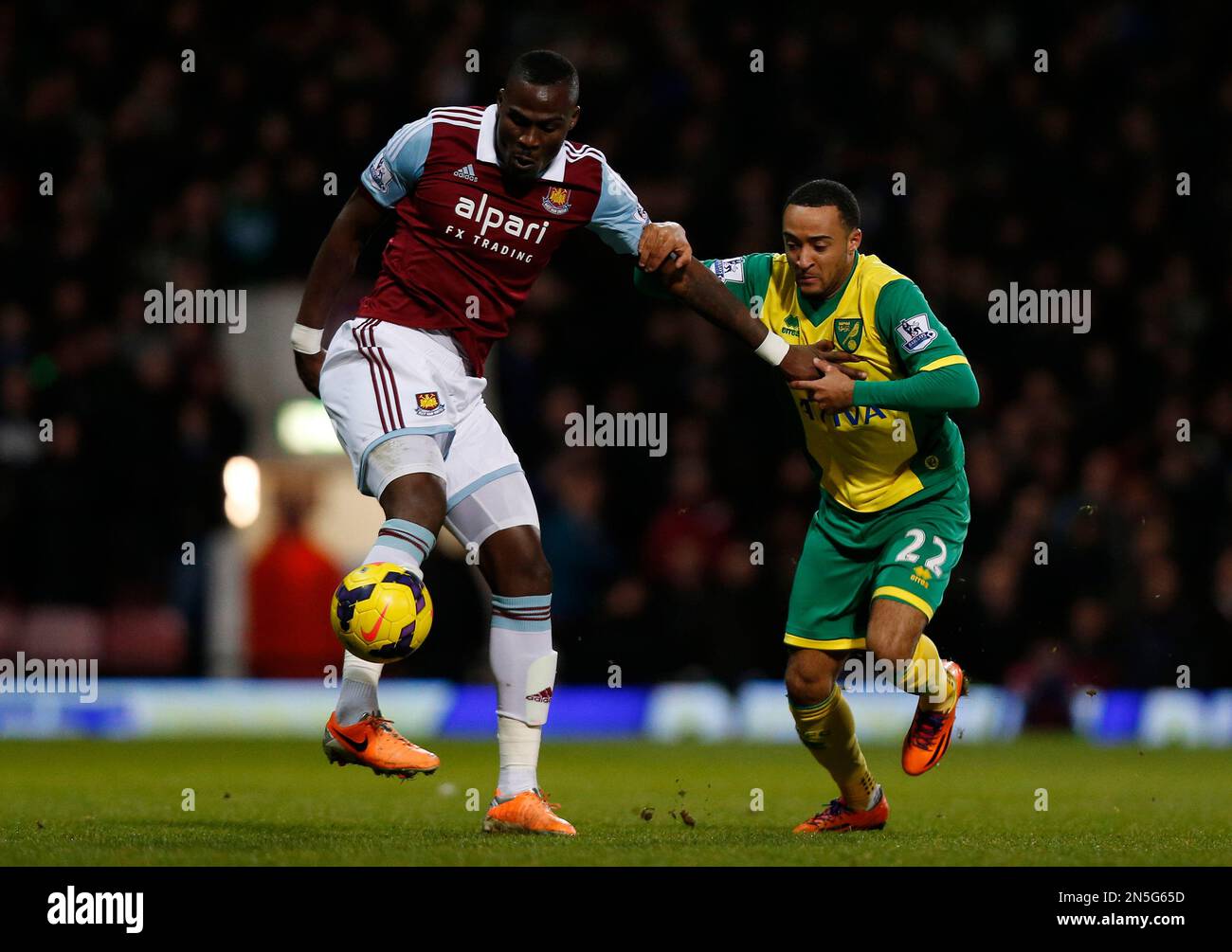 West Ham United's Guy Demel, left, competes with Norwich City's Nathan ...