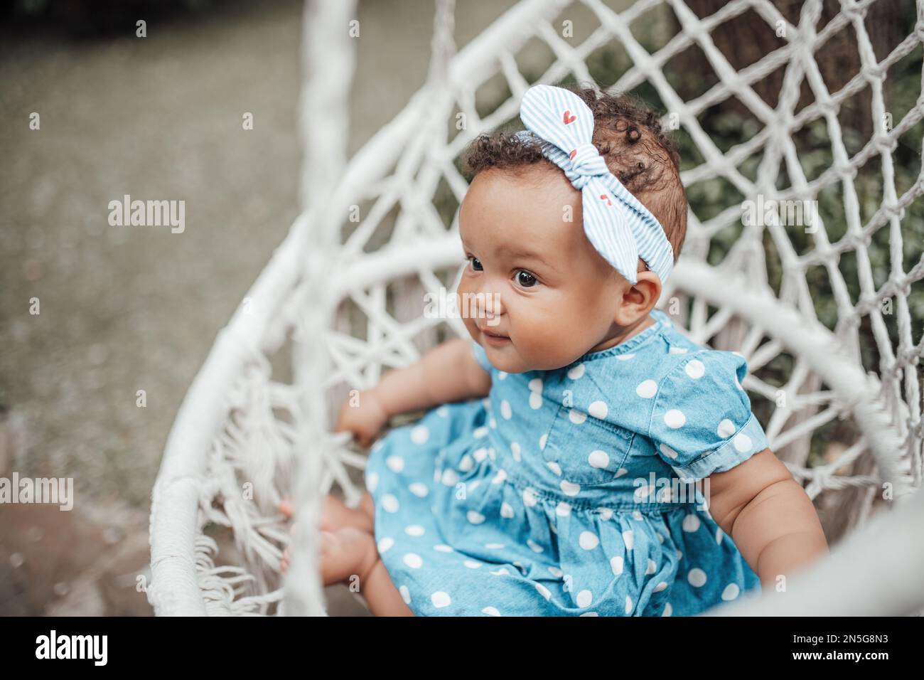 Swarthy little girl in blue polka dot dress has positive emotion ...