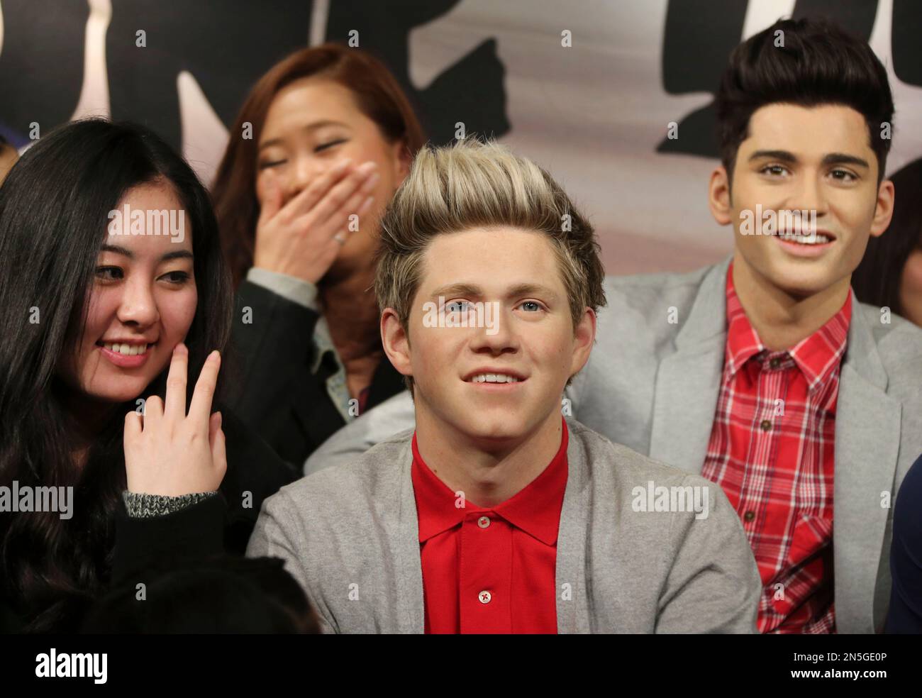 Fans pose for photo with wax figures of One Direction members Niall ...