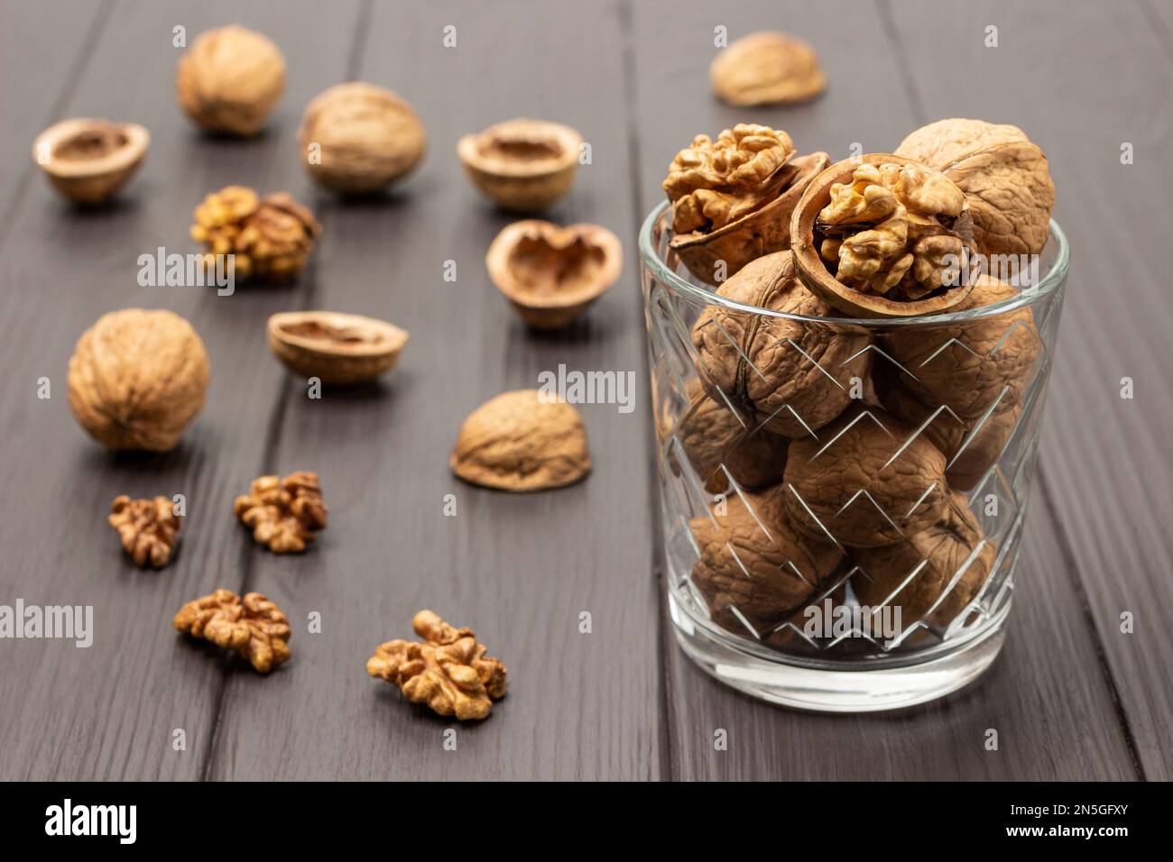 Walnuts in a glass. Walnut shells and kernel on table. Top view. Dark ...