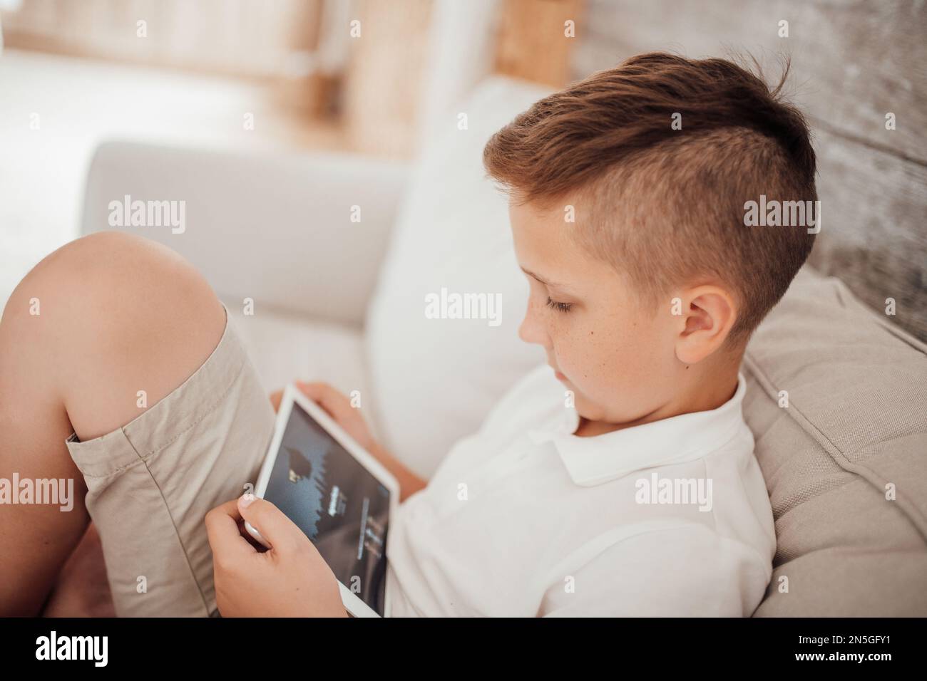 Gen Z boy using wireless technology at apartment in neutrals tones ...