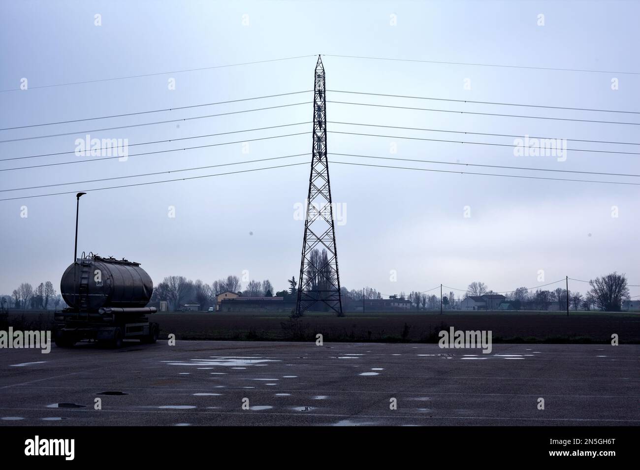 Tank in a parking lot by the edge of a fields with a pylon on a cloudy ...