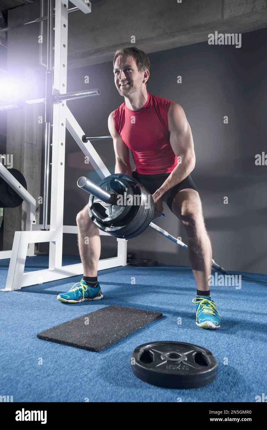 Mid adult man doing bent over row exercising with long barbell in the ...
