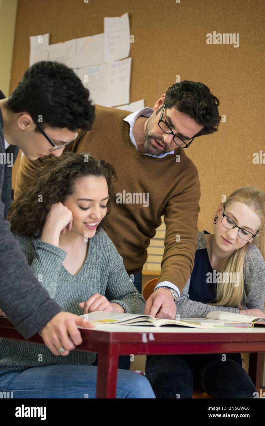 Teacher explaining something in a book to the students School, Bavaria ...