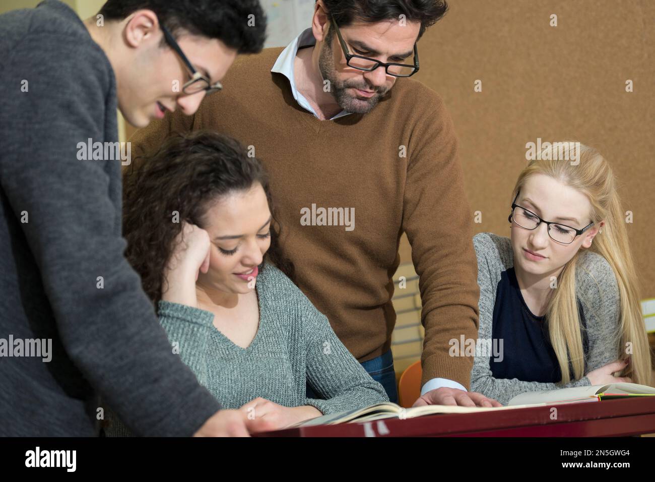 Teacher explaining something in a book to the students School, Bavaria ...