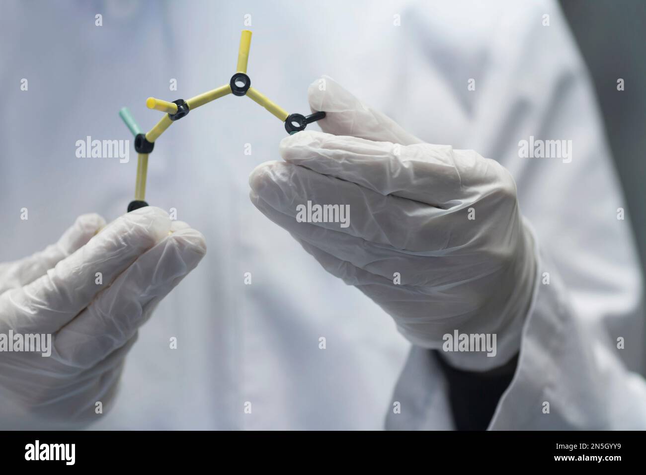 Mid section of a female scientist examining molecular model in a ...