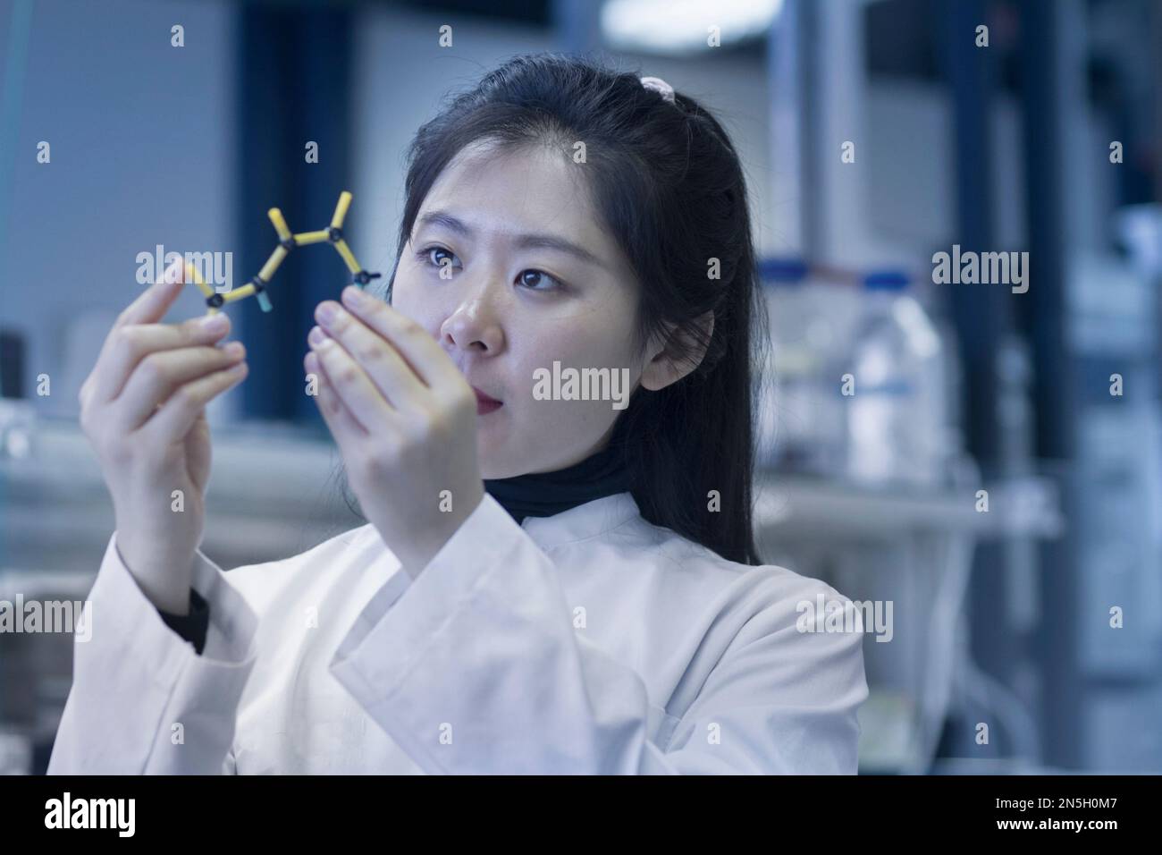 Young female scientist examining molecular model in a laboratory ...