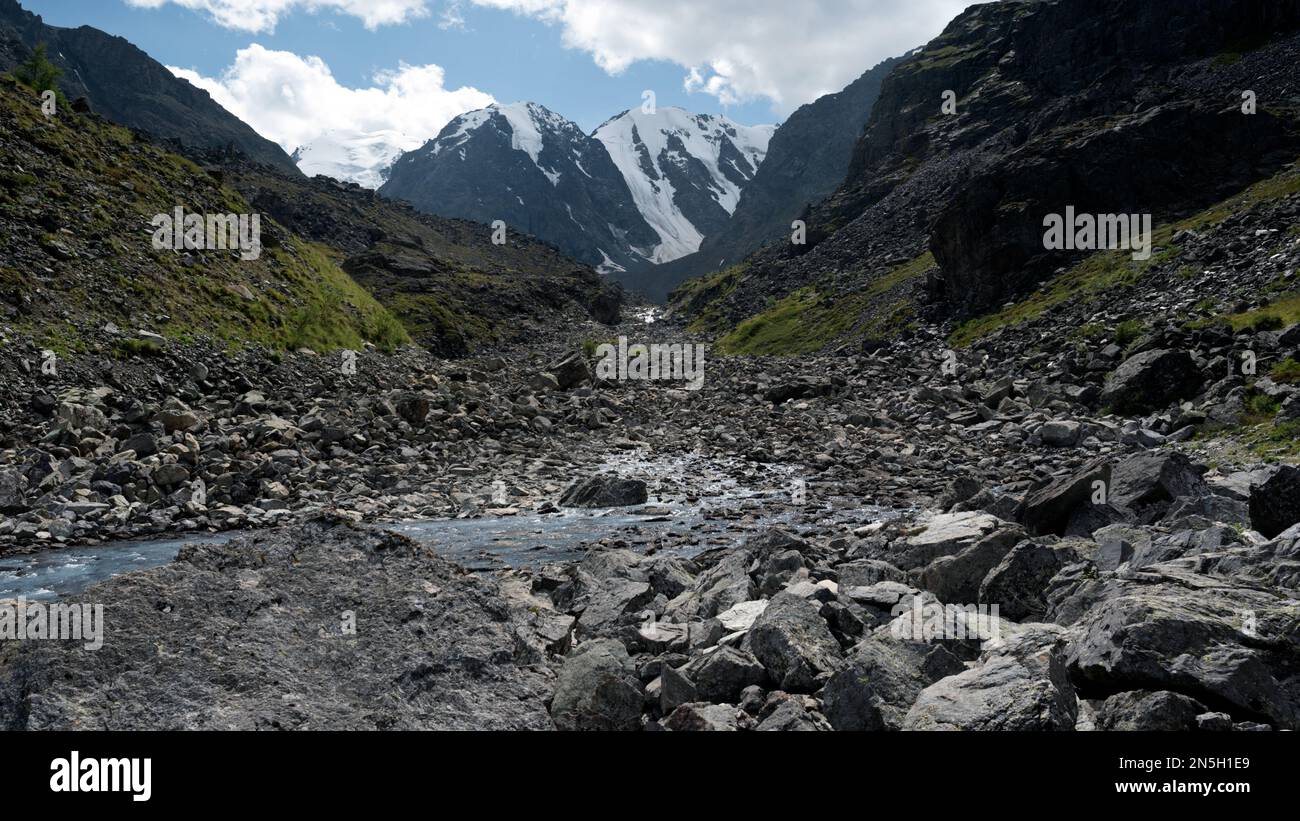 Alpine stream quickly flows under stones from high mountains with ...