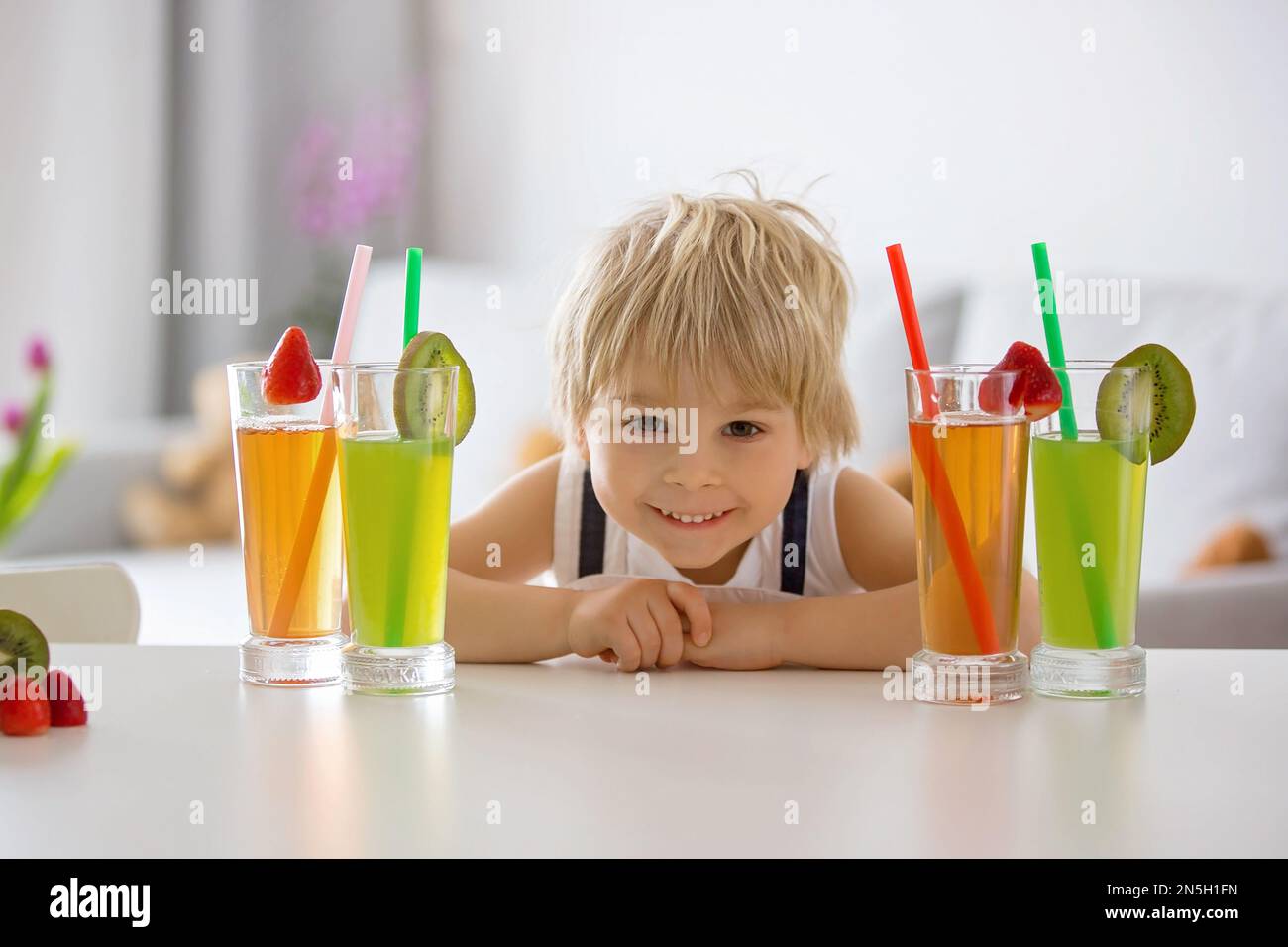 Cute toddler child, blond boy, drinking freshly made fruit juice at ...