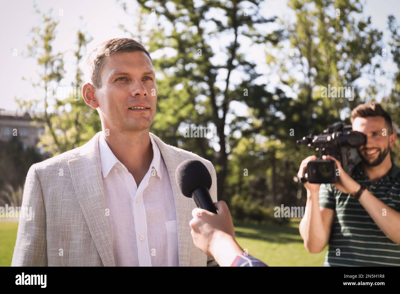 Professional journalist and operator with video camera taking interview ...