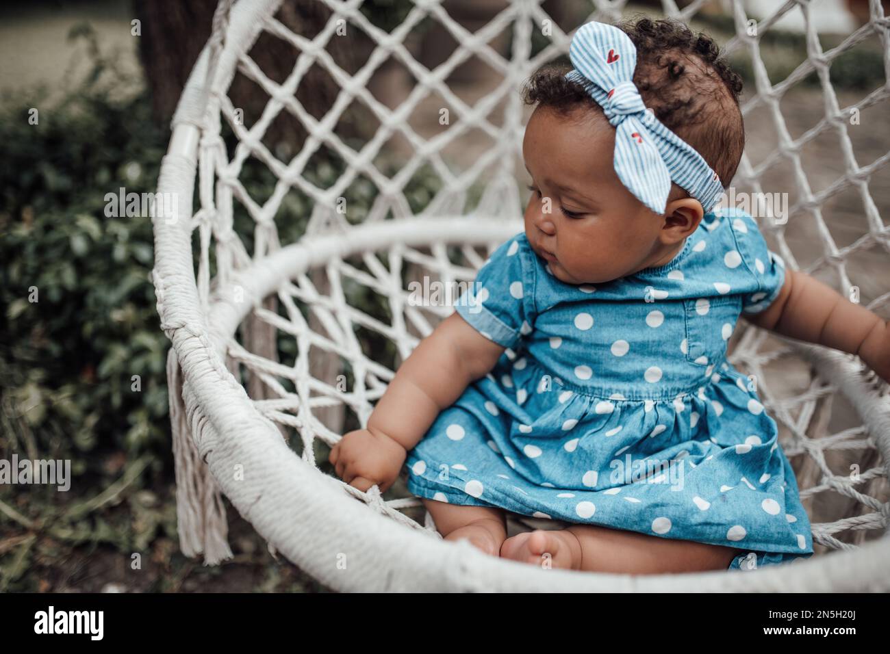 Swarthy little girl in blue polka dot dress has positive emotion ...